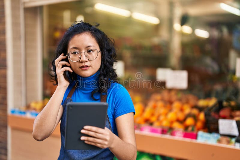 Young Chinese Woman Employee Talking on the Smartphone Using Touchpad ...
