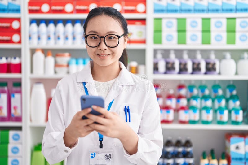 Young Chinese Woman Pharmacist Using Smartphone Working at Pharmacy ...