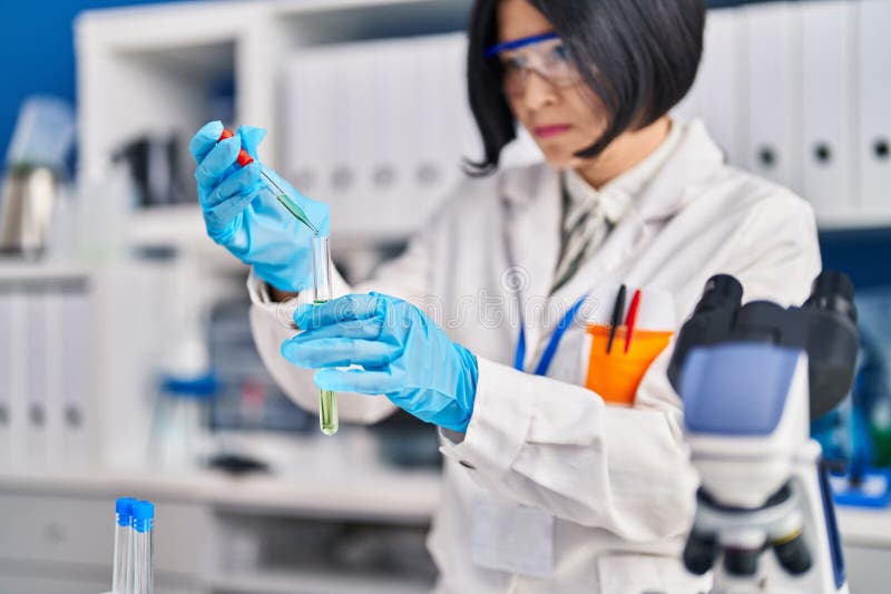 Young Chinese Woman Scientist Pouring Liquid on Test Tube at Laboratory ... Young Chinese Woman Scientist Pouring Liquid on Test Tube at Laboratory ...