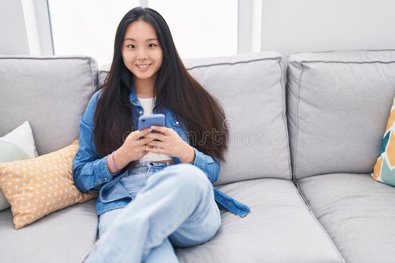 Young Chinese Woman Using Smartphone Sitting on Sofa at Home Stock ...