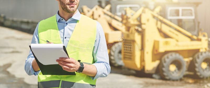 Young Civil Engineer Wearing Helmet Writing Report while Standing at ...
