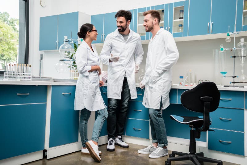 Young Colleagues in White Coats Standing and Talking in Chemical Lab ...