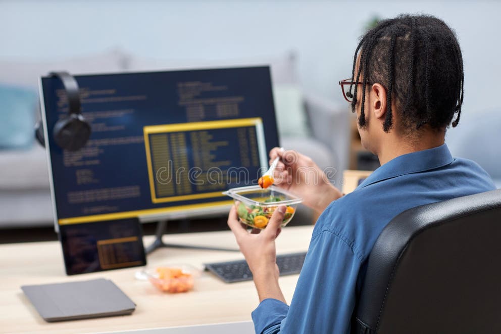 Young Computer Programmer Eating Takeout Lunch at Workplace while ...