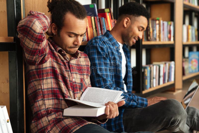 Young Concentrated Two African Men Reading Books Using Laptop Stock ...