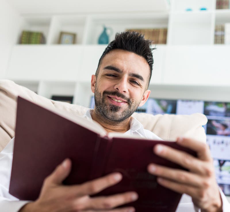 Young Confident Man Reading Book at Home Stock Photo - Image of beard ...