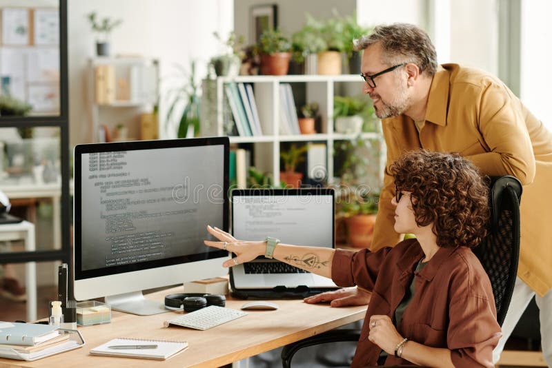 Young Confident Programmer Pointing At Data On Computer Screen Stock