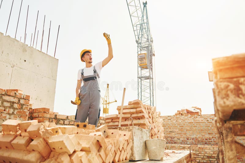 Young Construction Worker in Uniform is Busy at the Unfinished Building ...