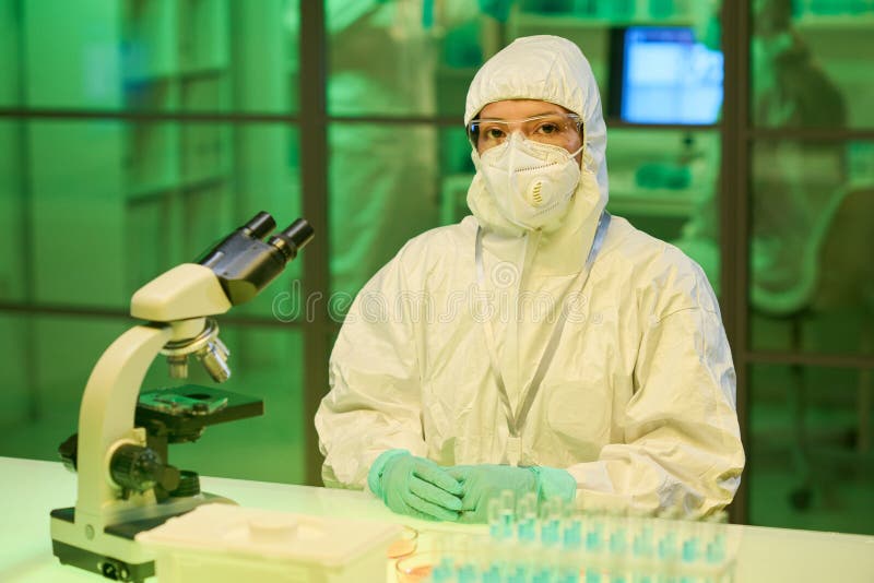 Young Contemporary Scientist in Biohazard Suit Sitting by Workplace in ...