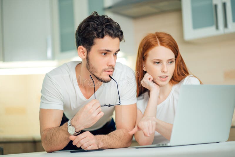 Couple Browsing Internet Together Sitting at Table and Smiling and Read ...