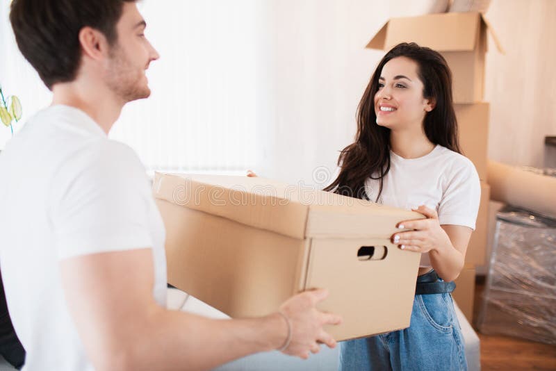 Young Couple Carrying Big Cardboard Box At New Home Moving House Stock