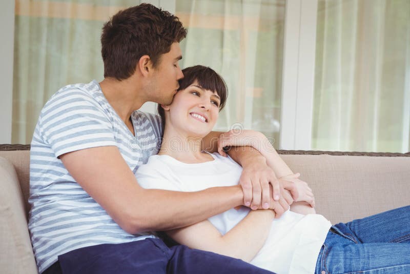 Young Couple Cuddling on Sofa Stock Photo - Image of homey, adorable ...