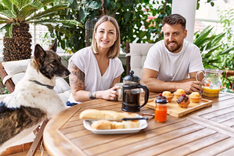 Young Couple with Dog Smiling Happy Having Breakfast at Terrace Stock ...