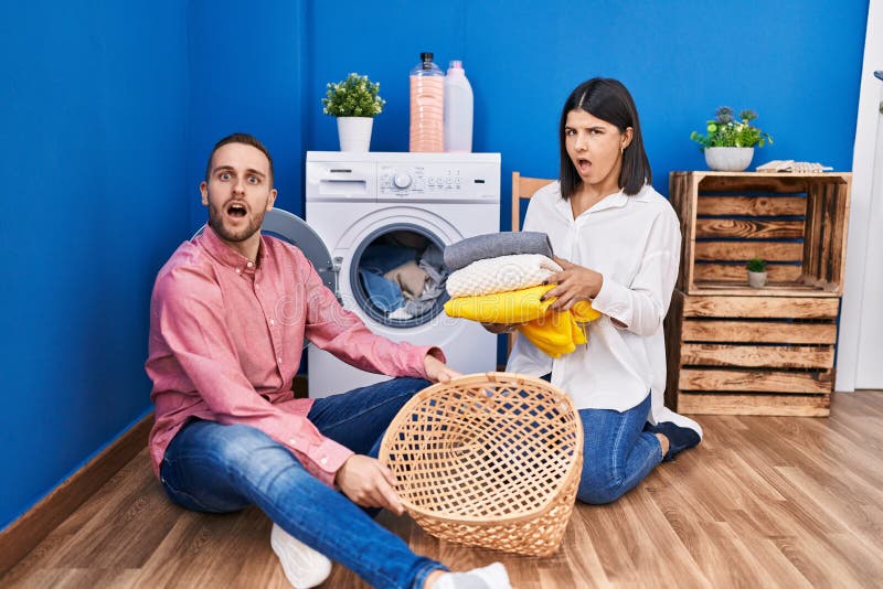 Young Couple Doing Laundry at Home in Shock Face, Looking Skeptical and ...