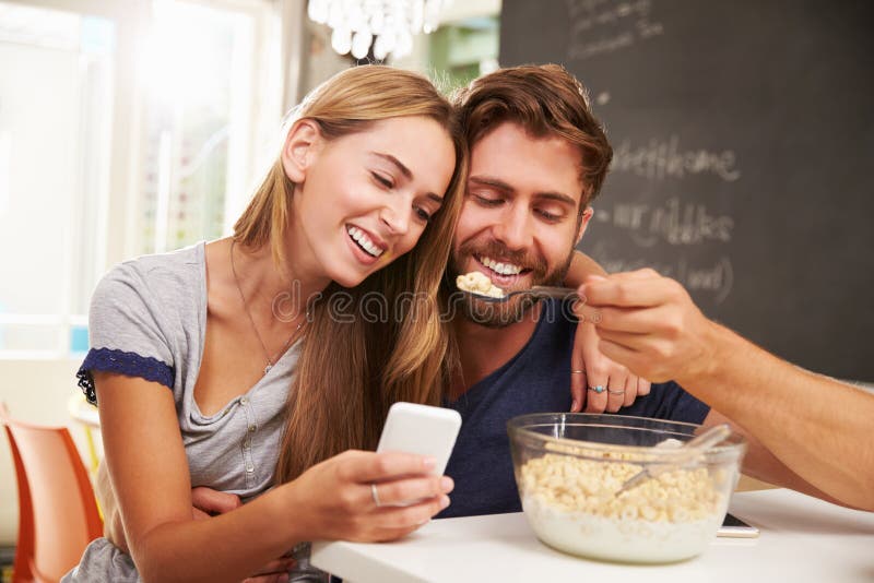 Young Couple Eating Breakfast Whilst Using Mobile Phones Stock Photo ...