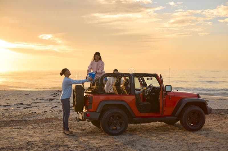 Young Couple with Friends Unloading Cool Box from Car at Beach at ...