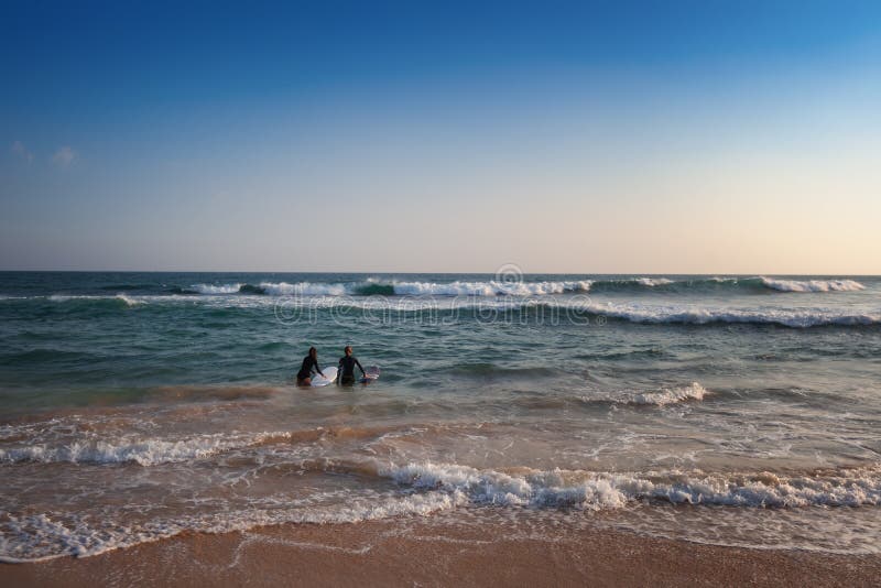 Young Couple Going into Ocean Waves with Surfboards on Beautiful ...