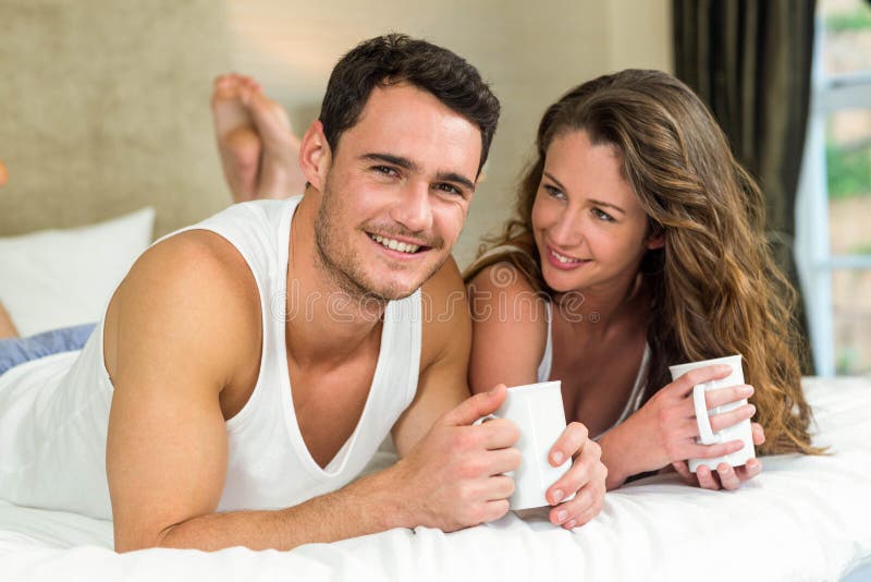 Young Couple Having Cup of Coffee on Bed Stock Image - Image of homey ...