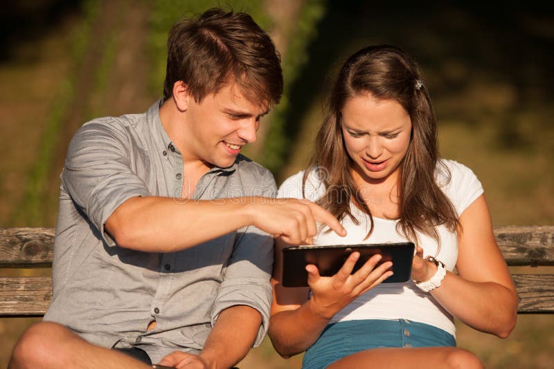 Young Couple Having Fun on a Bench in Park while Socializing Over Web ...