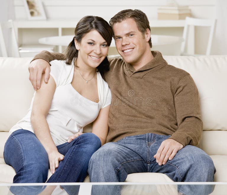 Young Couple Hugging on Couch Stock Photo - Image of indoors, looking ...