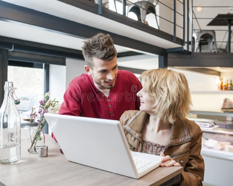 Young Couple Looking at Each Other while Using Laptop in Cafe Stock ...