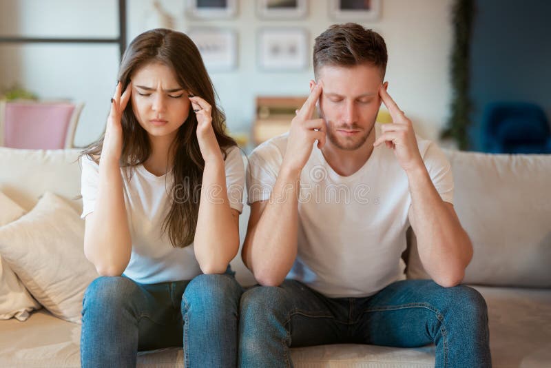 Young Couple Man And Woman Sitting On The Sofa Both Looking Tired And