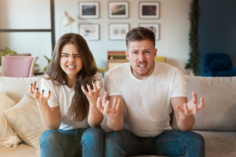 Young Couple Man And Woman Sitting On The Sofa Both Looking Mad