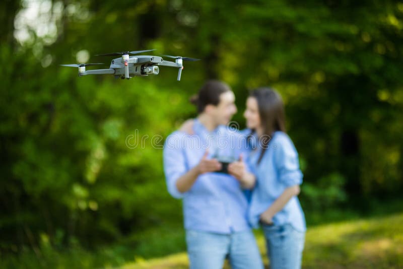 Young Couple Navigating a Flying Drone with Remote Control. Man and ...