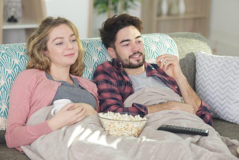 Young Couple with Popcorn on Sofa Watching Movie Stock Photo - Image of ...