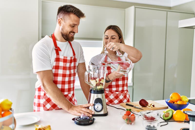 Young Couple Pouring Water Making Smoothie Cooking at Kitchen Stock ...