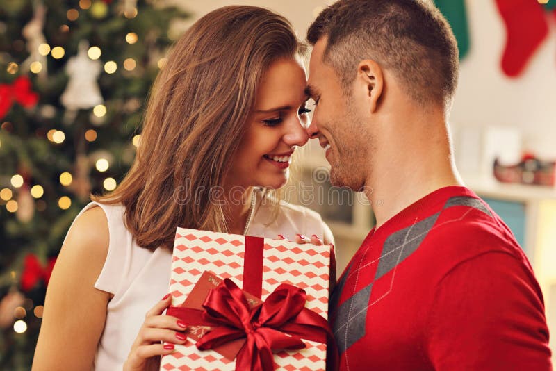 Young Couple with Present Over Christmas Tree Stock Photo - Image of ...
