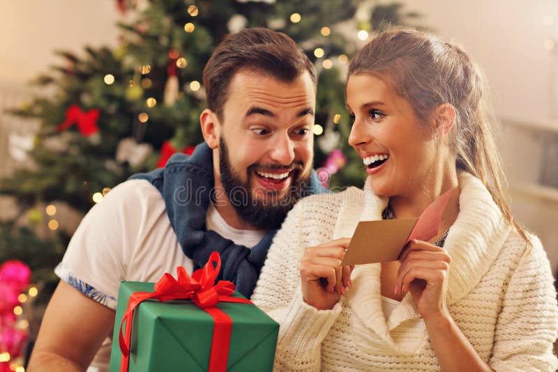 Young Couple with Present Over Christmas Tree Stock Photo - Image of ...