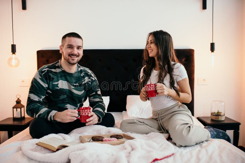 Young Couple Relaxing on a Bed with Warm Drinks Stock Photo - Image of ...