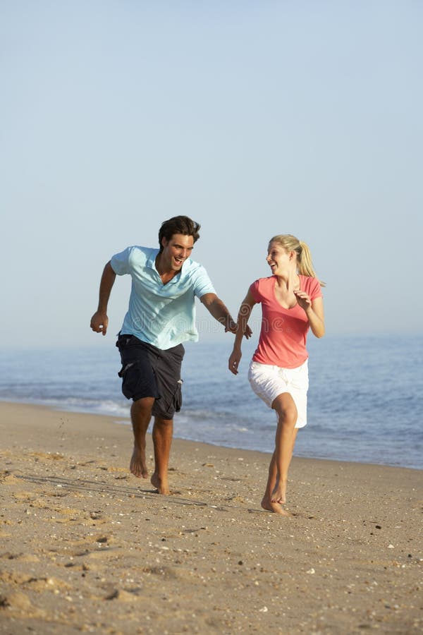 Young Couple Running Along Beach Stock Image - Image of cute, female ...