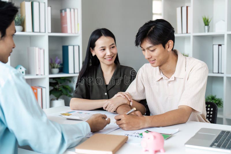 Young Couple Signing Financial Documents with Advisor in Modern Office Setting Stock Image ...