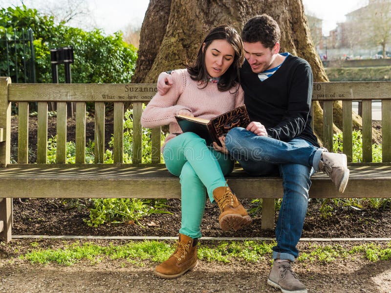 Young Couple Sitting on a Bench Reading a Book Stock Image - Image of ...