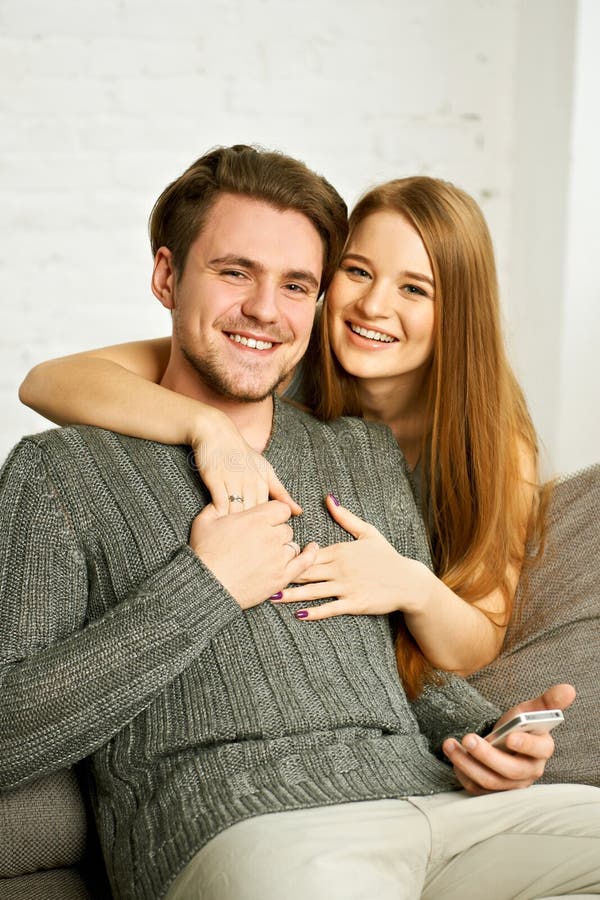 Young Couple Sitting on Sofa and Hugging Stock Image - Image of smile ...