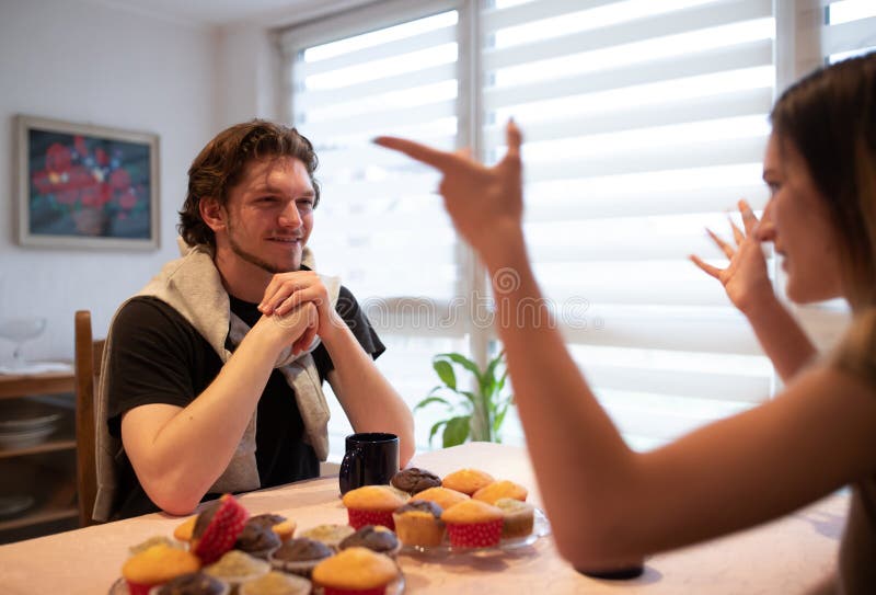 Young Couple Talking at Table at Home Stock Photo - Image of raised ...