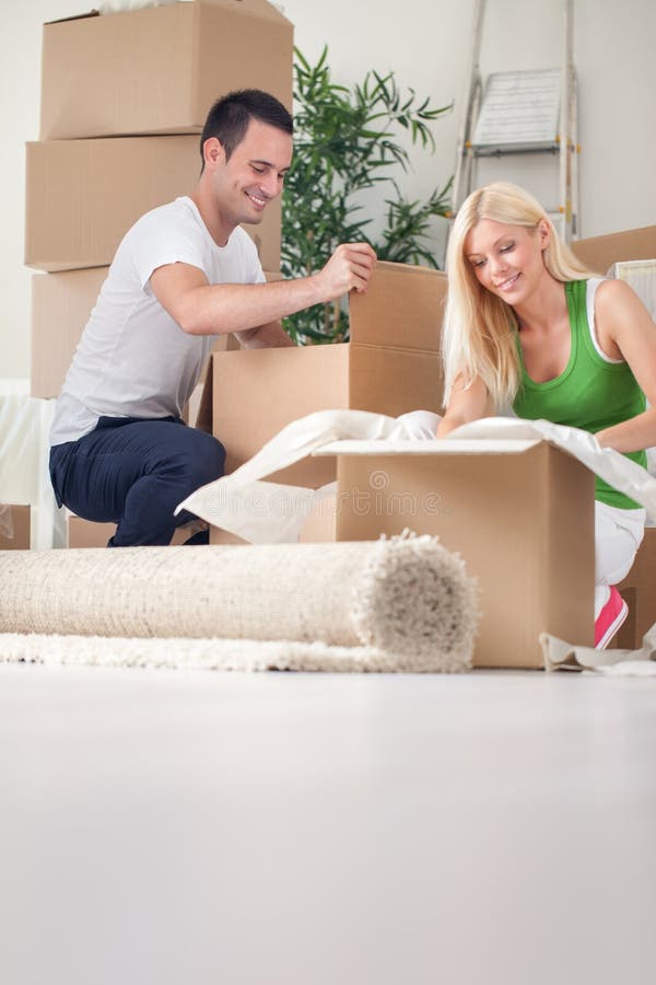 Young Couple Unpacking Boxes Stock Image - Image of male, expressing ...