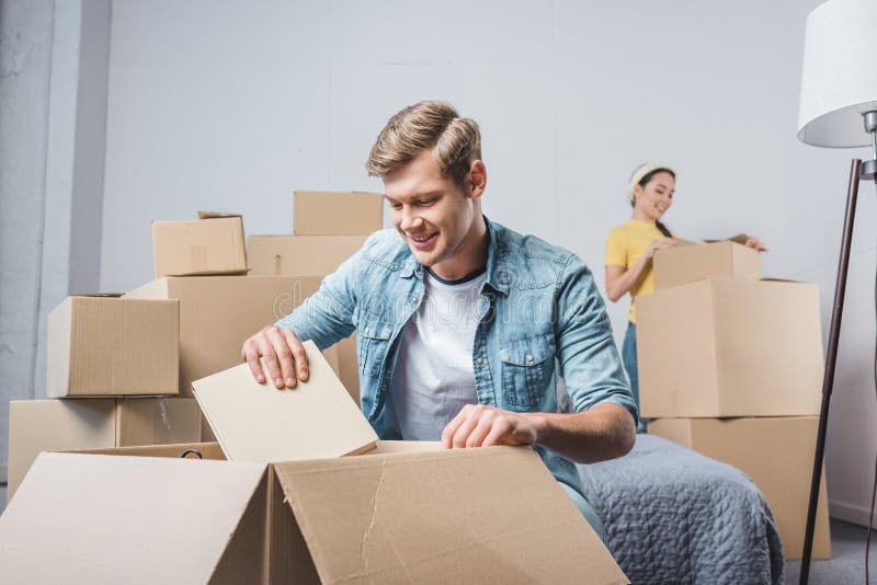 Young Couple Unpacking Boxes while Moving into Stock Image - Image of ...