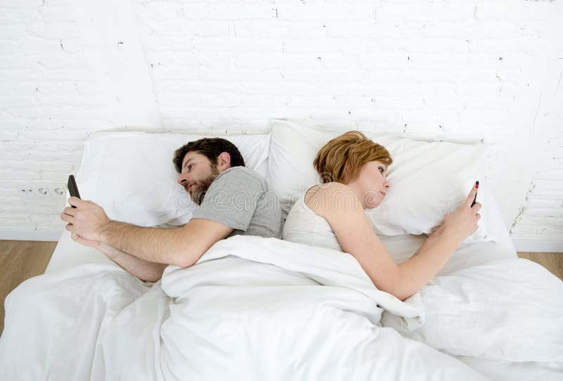 Young Couple Using Mobile Phone in Bed Ignoring Each Other in ...