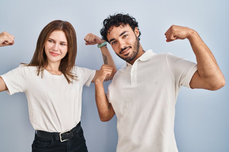 Young Couple Wearing Casual Clothes Standing Together Showing Arms