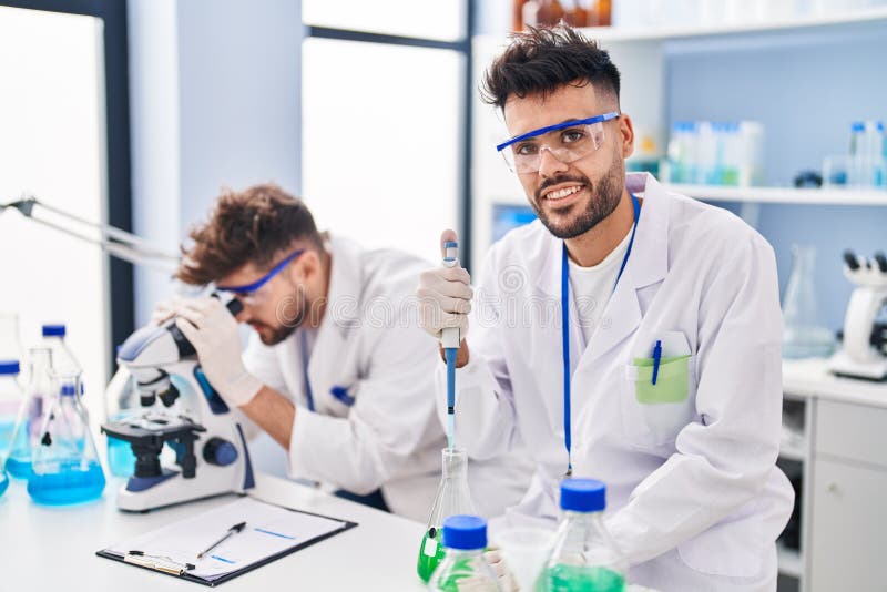 Young Couple Wearing Scientist Uniform Using Microscope and Pipette at ...