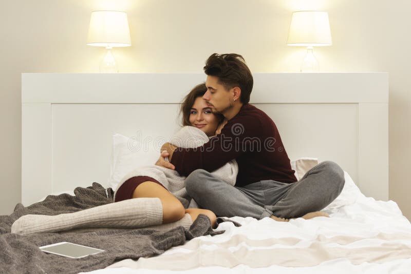 Young Couple Wearing Warm Sweaters Sitting on the Bed Stock Photo ...