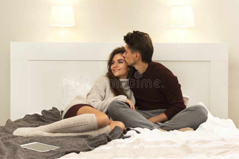 Young Couple Wearing Warm Sweaters Sitting on the Bed Stock Photo ...