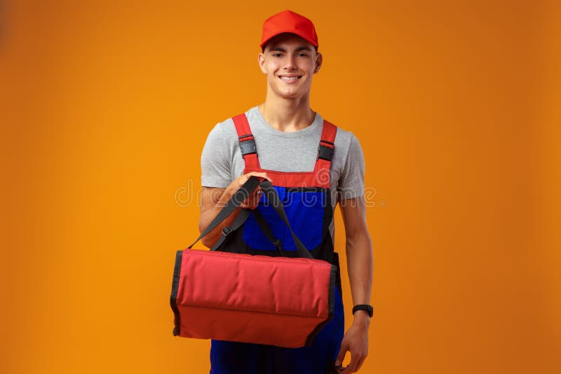 Young Courier in Uniform with Thermo Bag on Yellow Background Stock ...