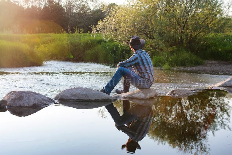 Young Cowboy Admires The Sunset In The Spring Evening On The Riv Stock ...