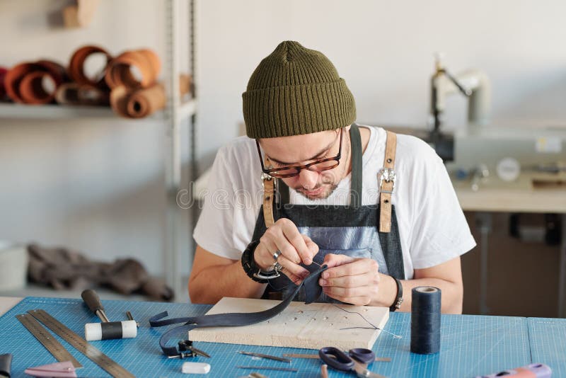 Young Creative Leatherworker Bending Over Table while Sewing New Item ...