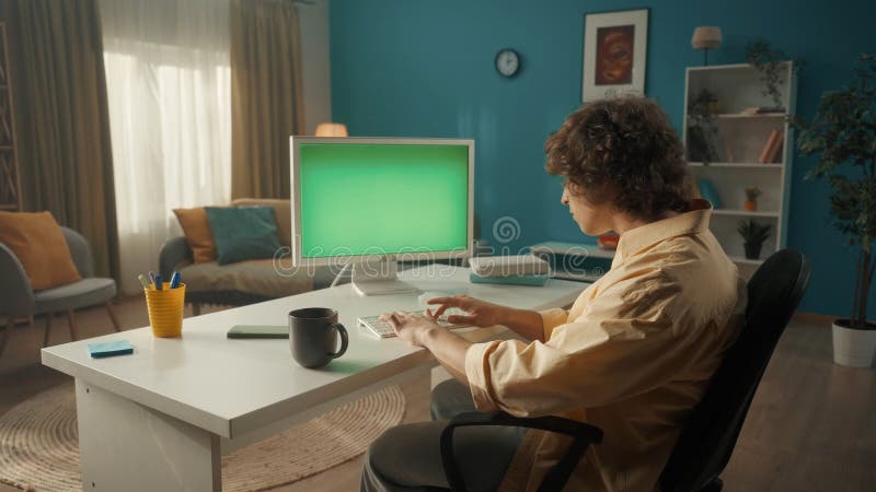 A Young Curly Guy is Working on a Computer with a Green Screen. a Man ...
