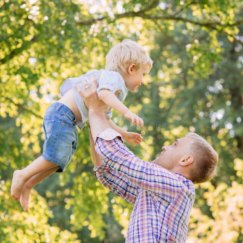 Young Dad Playing with His Son in the Park by Throwing Him Up Stock ...