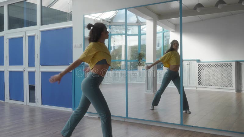 A Young Dancer Woman in a Dance Studio is Warming Up in Front of the ...